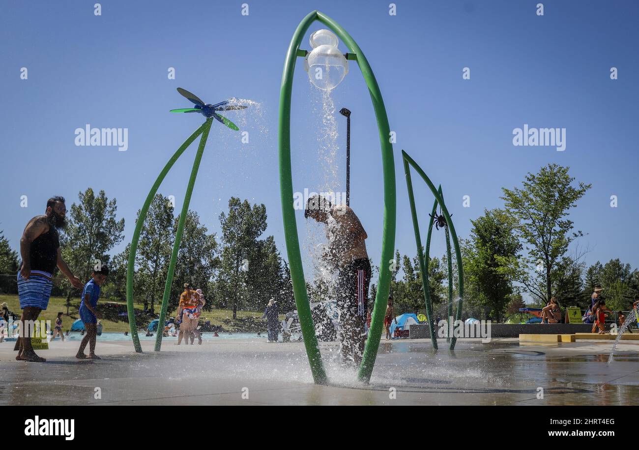 A man stands under a water feature trying to beat the heat at a splash ...