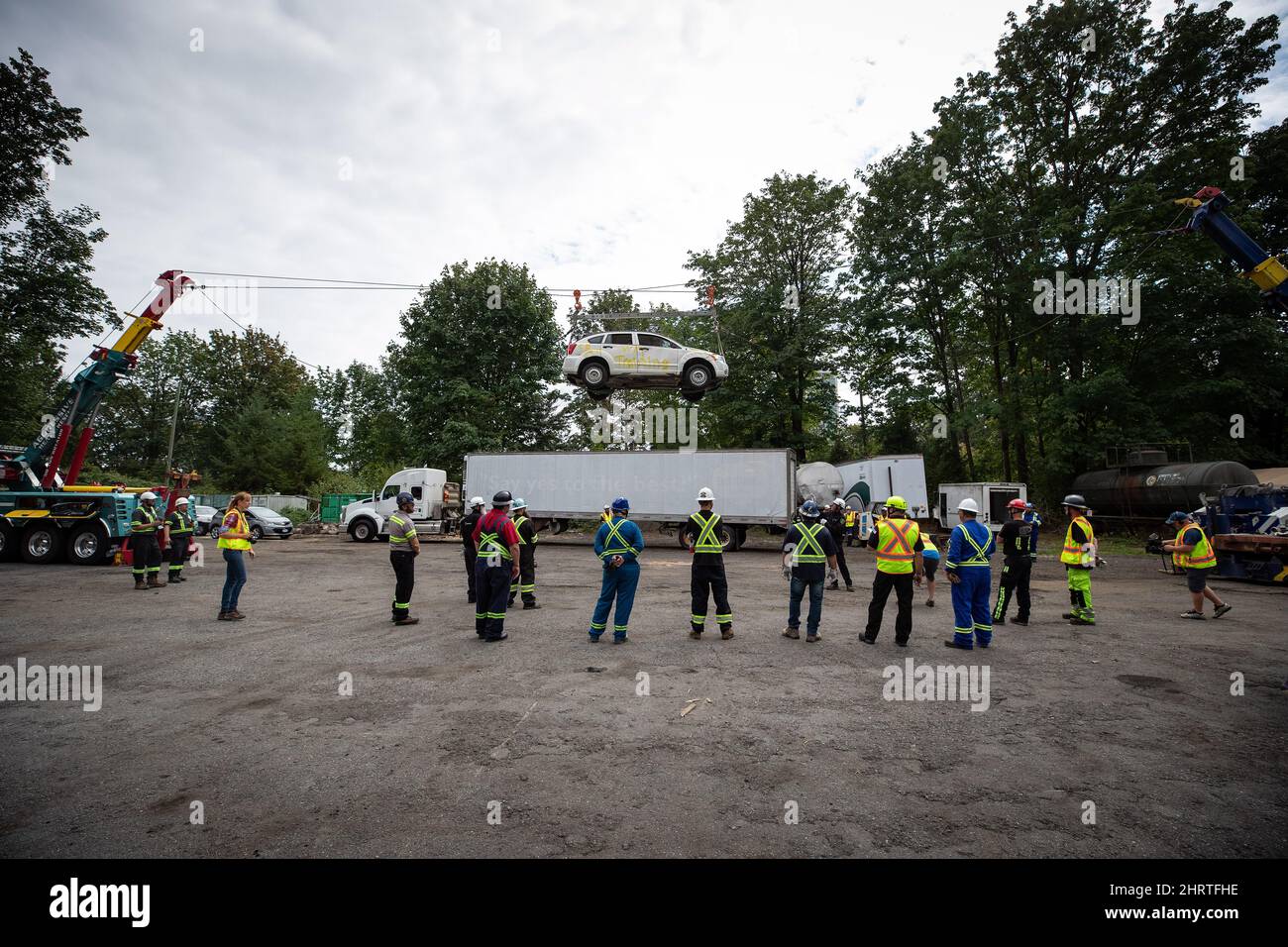 Heavy duty tow truck operators watch as a vehicle is lifted by winch ...