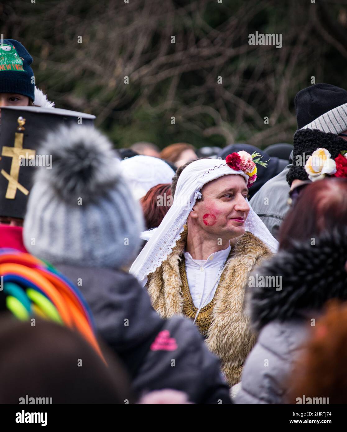 The people in traditional folk costumes and masks walk on the street at ...