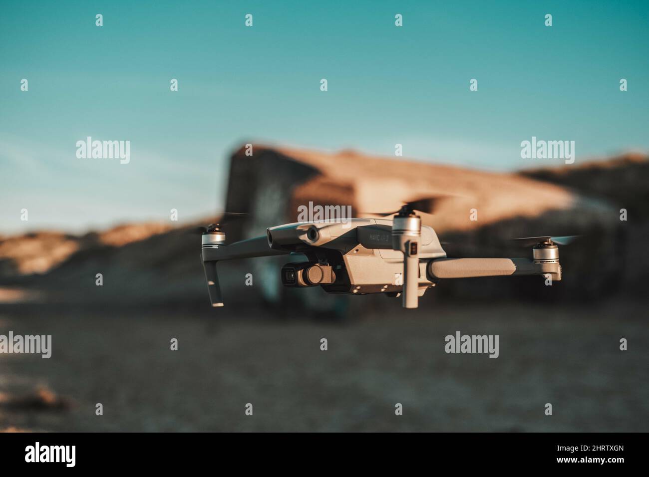 Closeup of a modern drone with a camera in the air at a beach with a ...