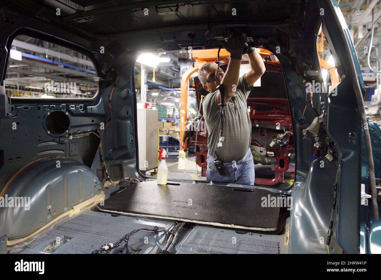Employees work on the newest minivan version on the assembly line as ...