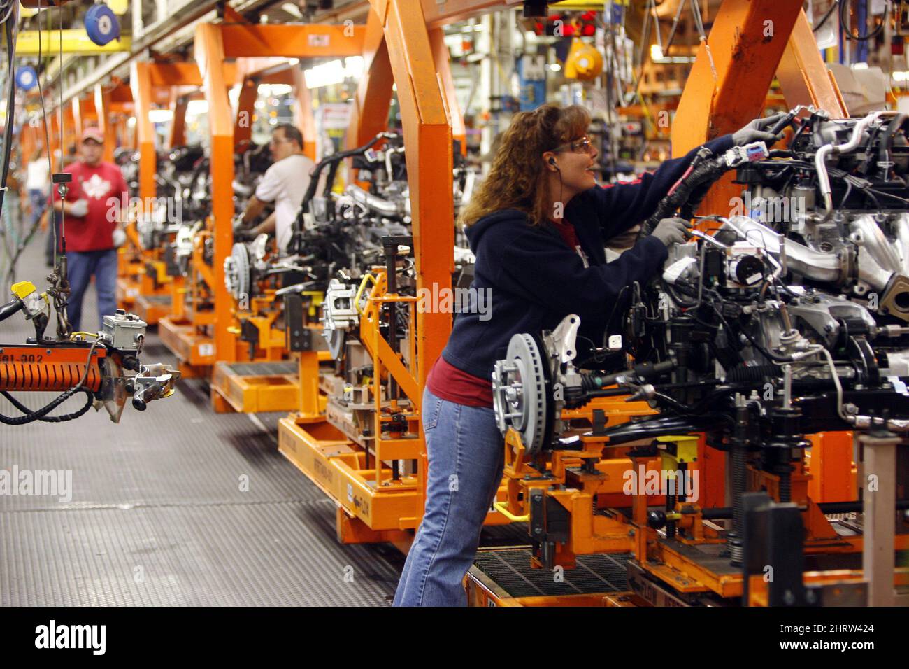 Employees work on the newest minivan version on the assembly line as ...