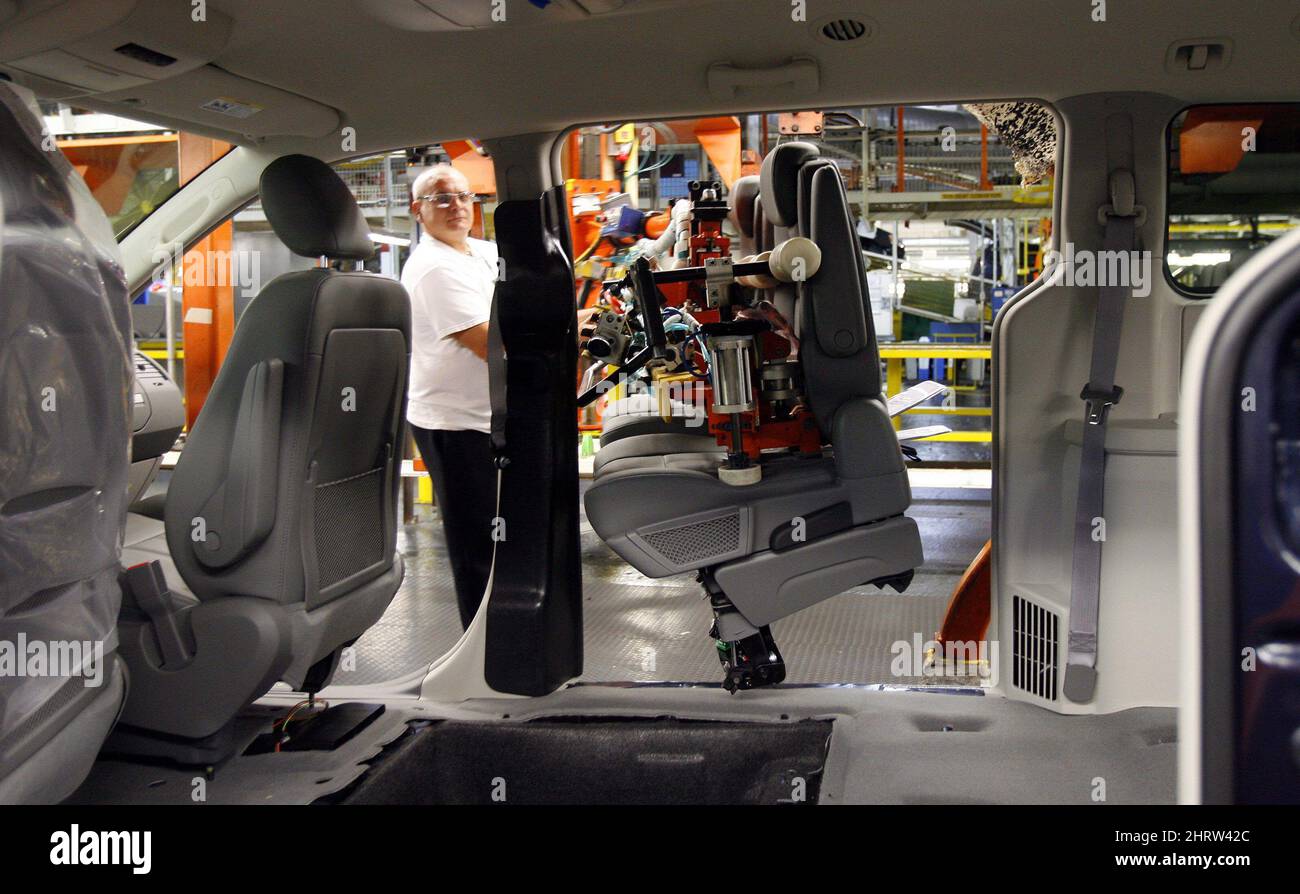 Employees work on the newest minivan version on the assembly line as ...