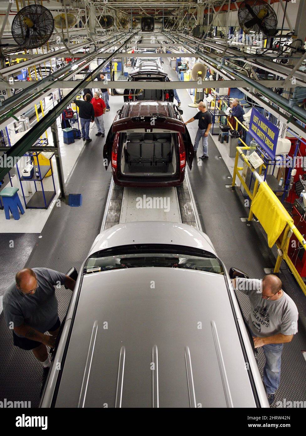 Employees work on the newest minivan version on the assembly line as ...