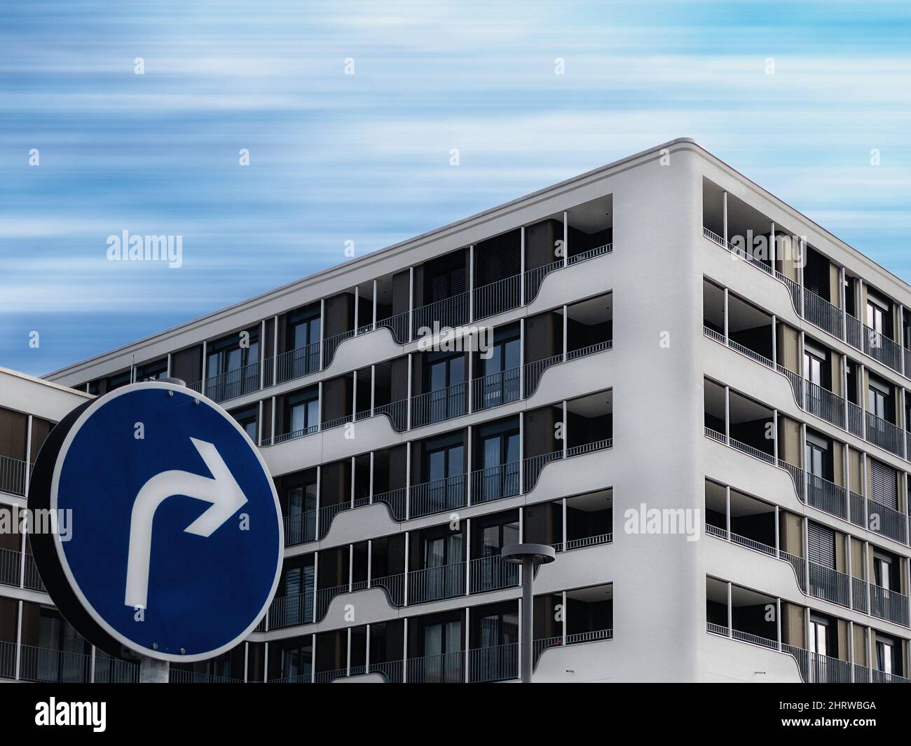 Road sign showing the right direction in front of a modern mid-rise ...