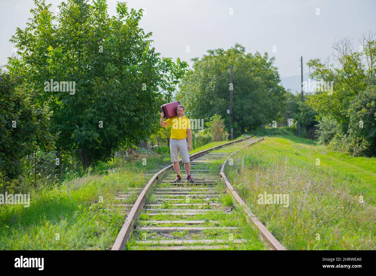 a slow man in a yellow t-shirt walks on the rails Stock Photo - Alamy