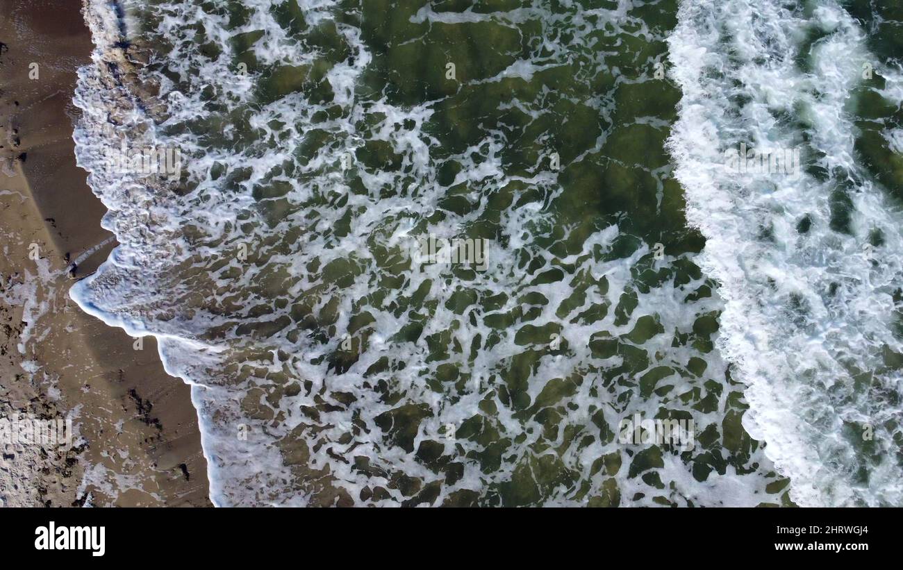 Aerial drone view flight over sea waves that roll onto sandy shore ...