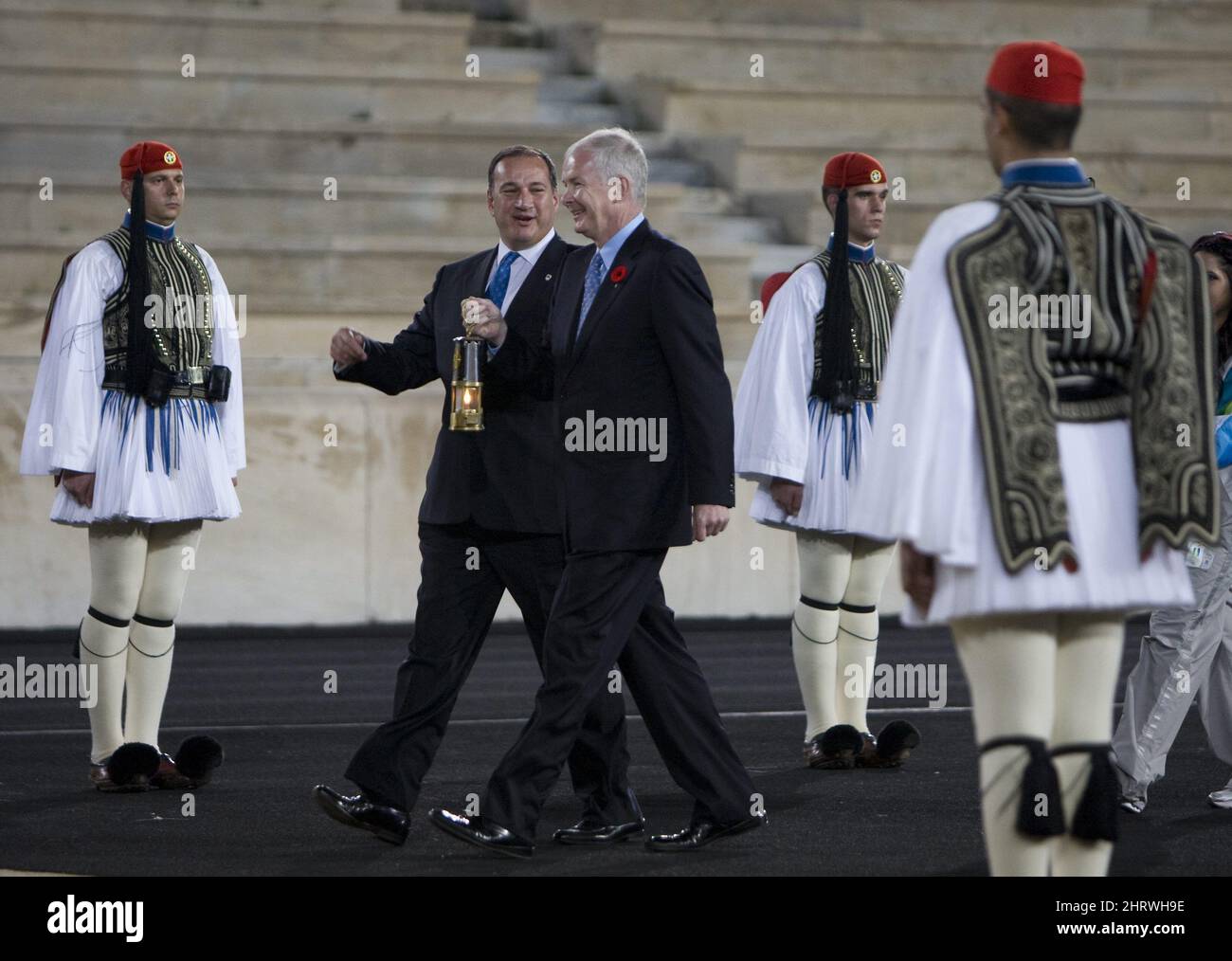 VANOC Chief Executive Officer John Furlong, centre, carries the Olympic ...