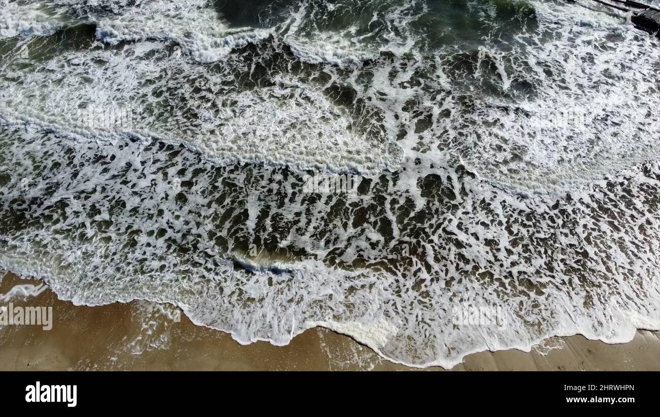 Aerial drone view flight over waves that roll onto the sandy shore. Top ...