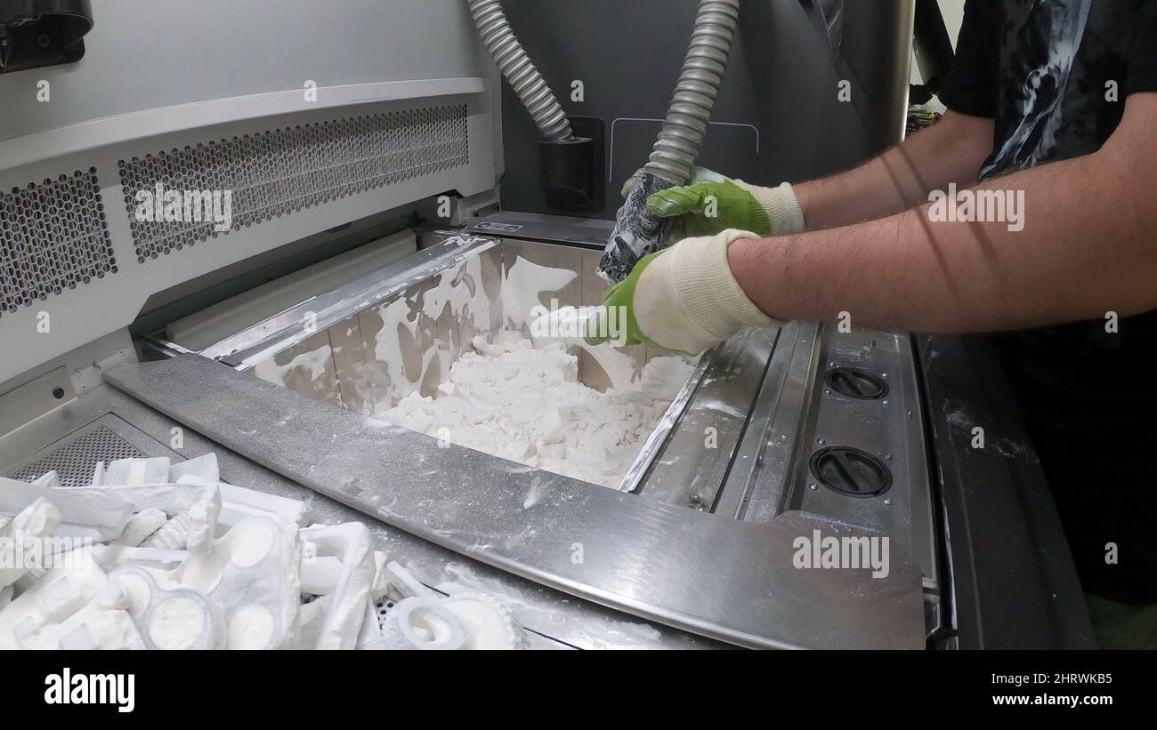Man cleans details printed on industrial 3D printer from white plastic ...