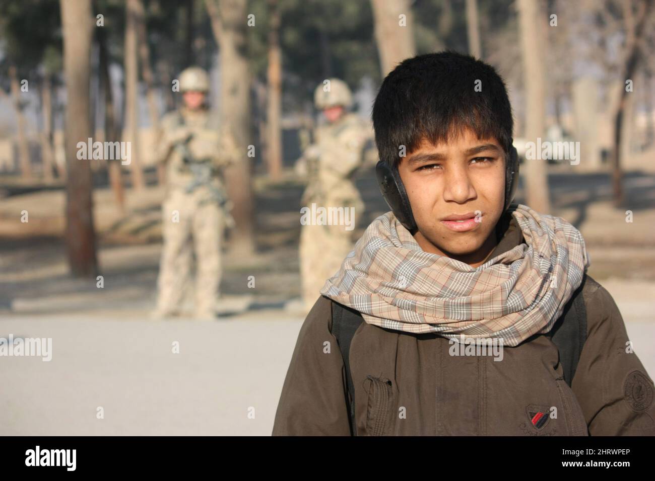 A young man walks past two Canadian soldiers at an Afghan National Army ...