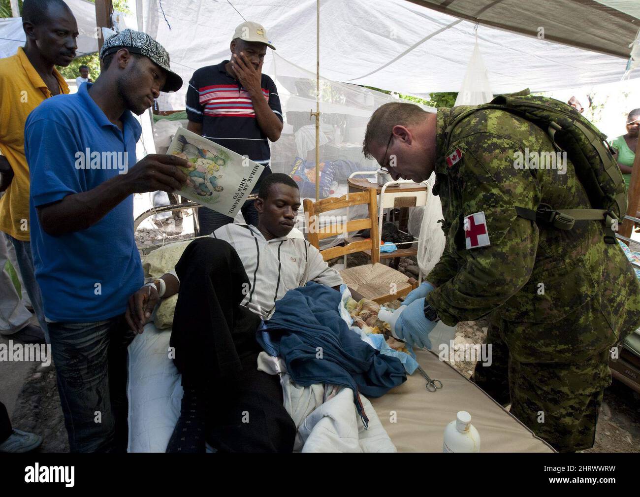 Petty Officer Paul Spracklin is watched as he tends to a man with a ...