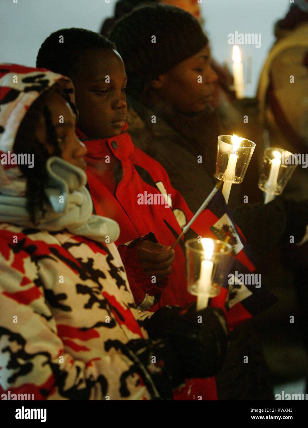 Eleonora Pierre, left to right, her brother Al'x Pierre and mother Edwidge Pierre hold candles ...