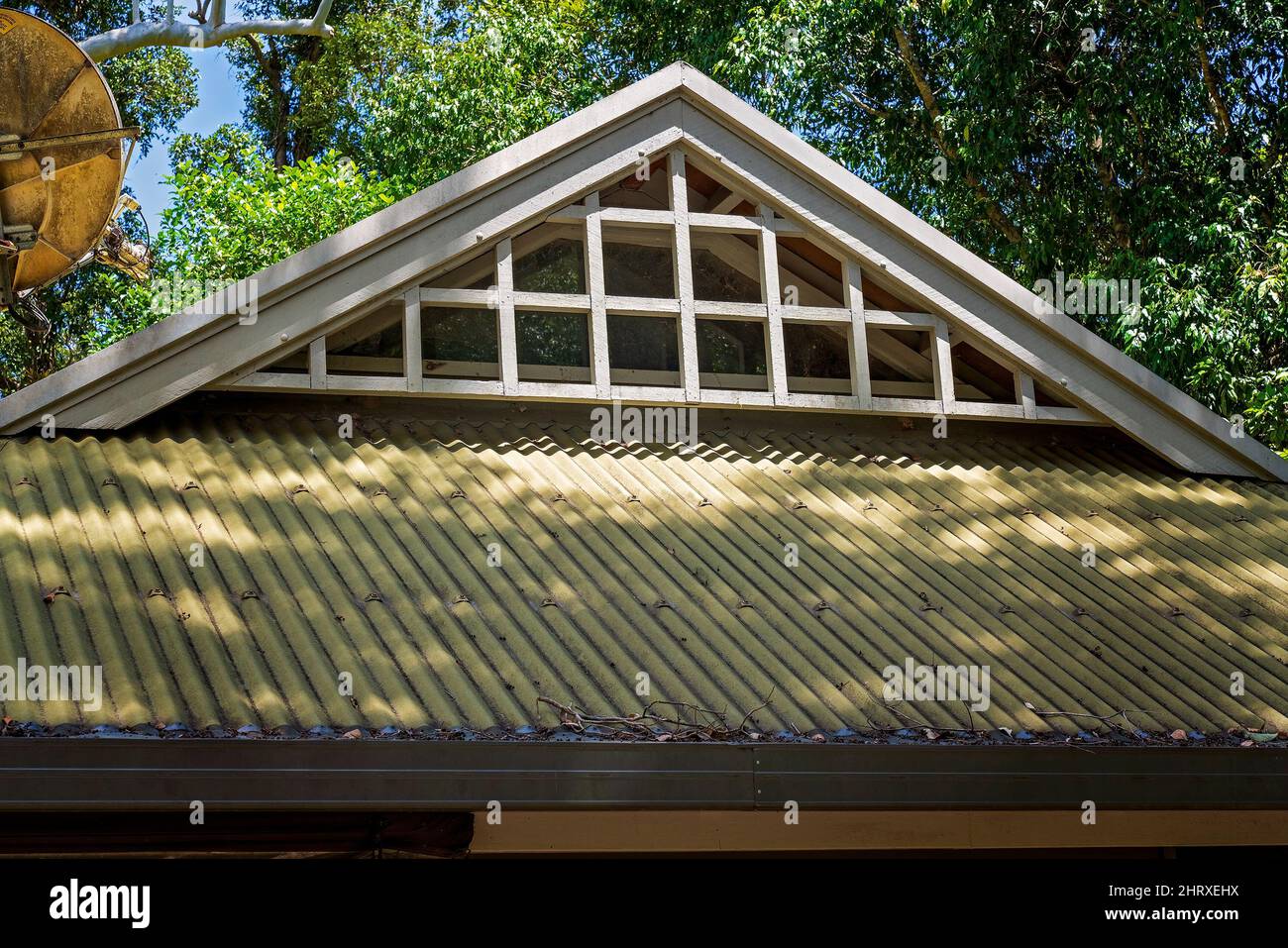 A triangle shaped roof line of a building surrounded by tropical trees ...