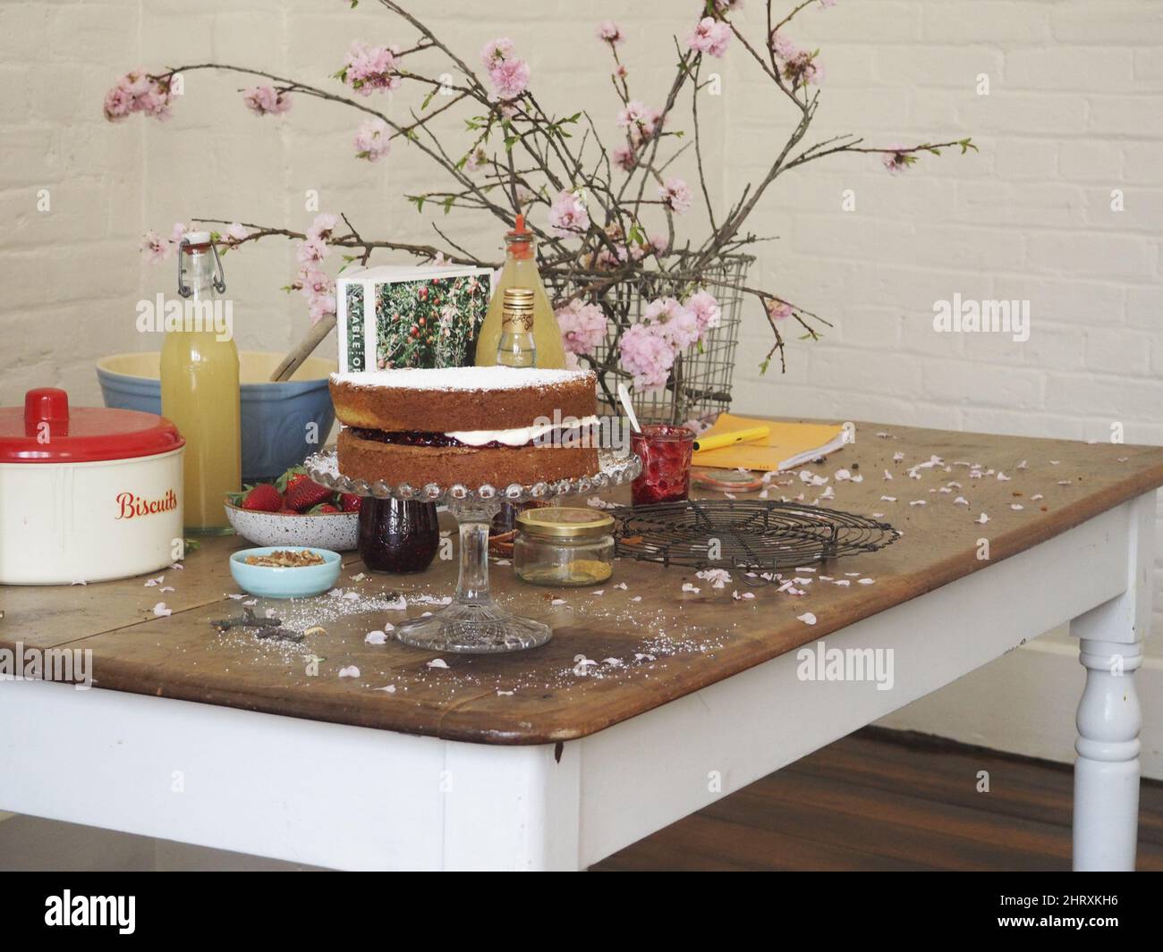 Messy table with cake ingredients and flowers during preparation Stock ...