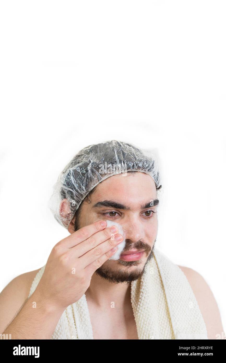 Portrait of a young adult man with a hair mask wiping off the facemask ...