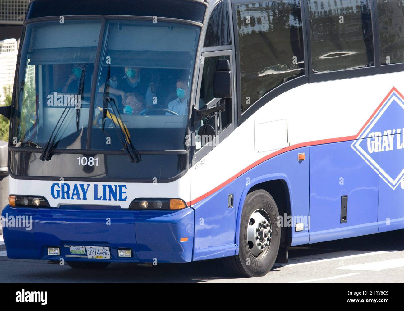 Corrections officers and a bus driver are seen at the front of a bus ...