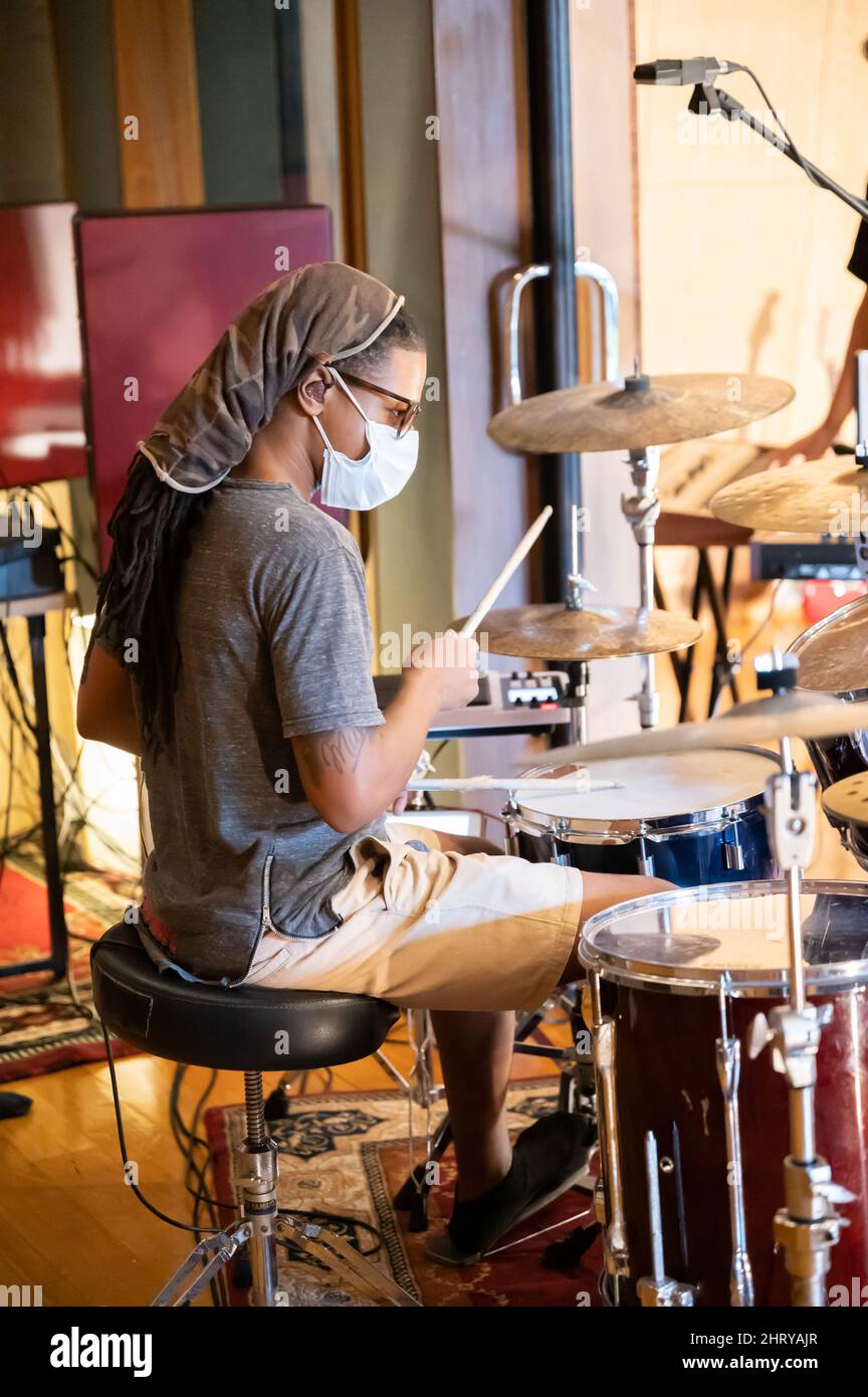 Vertical shot of the female drummer playing drums wearing face mask ...