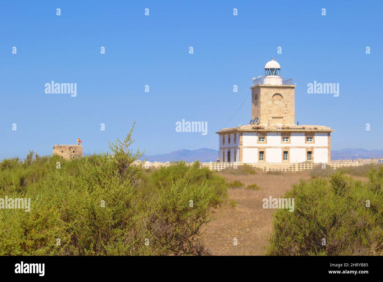 Tabarca Lighthouse on a hill covered in greenery under a blue sky and ...