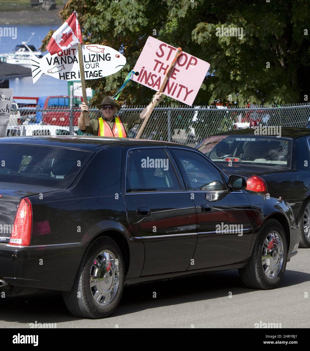 Protesters wave signs at Prime Minister Stephen Harper's motorcade ...