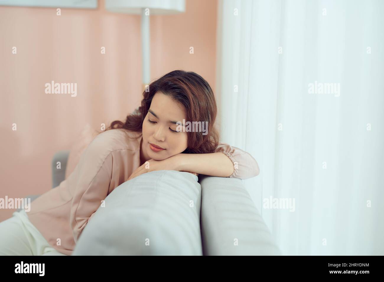 Tired attractive woman taking a nap on a sofa, close up of her face ...