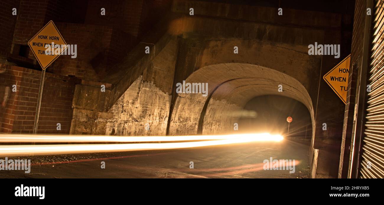 Tunnel at night with a car approaching with bright headlights Stock ...