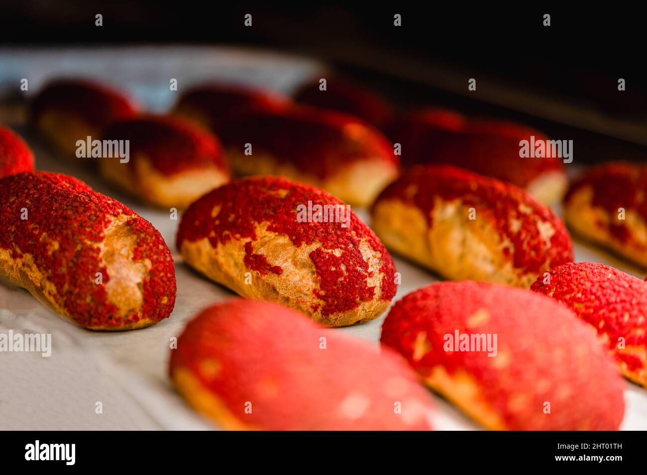 Closeup of delicious eclairs with red strawberry crumble on a pan with ...