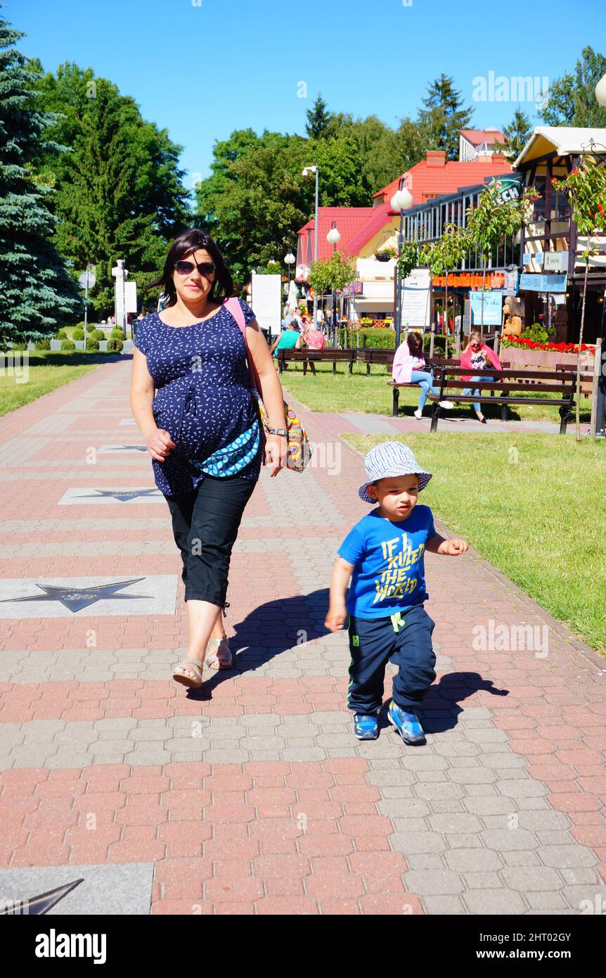 Woman and her little boy walking on a footpath with stars in the town ...