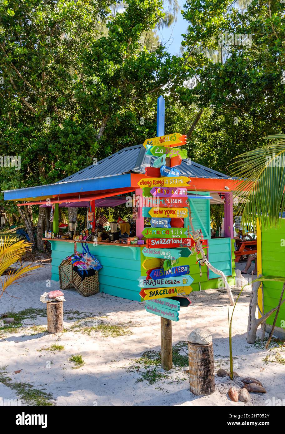 Colorful sign post in front of a tropical beach bar Stock Photo - Alamy
