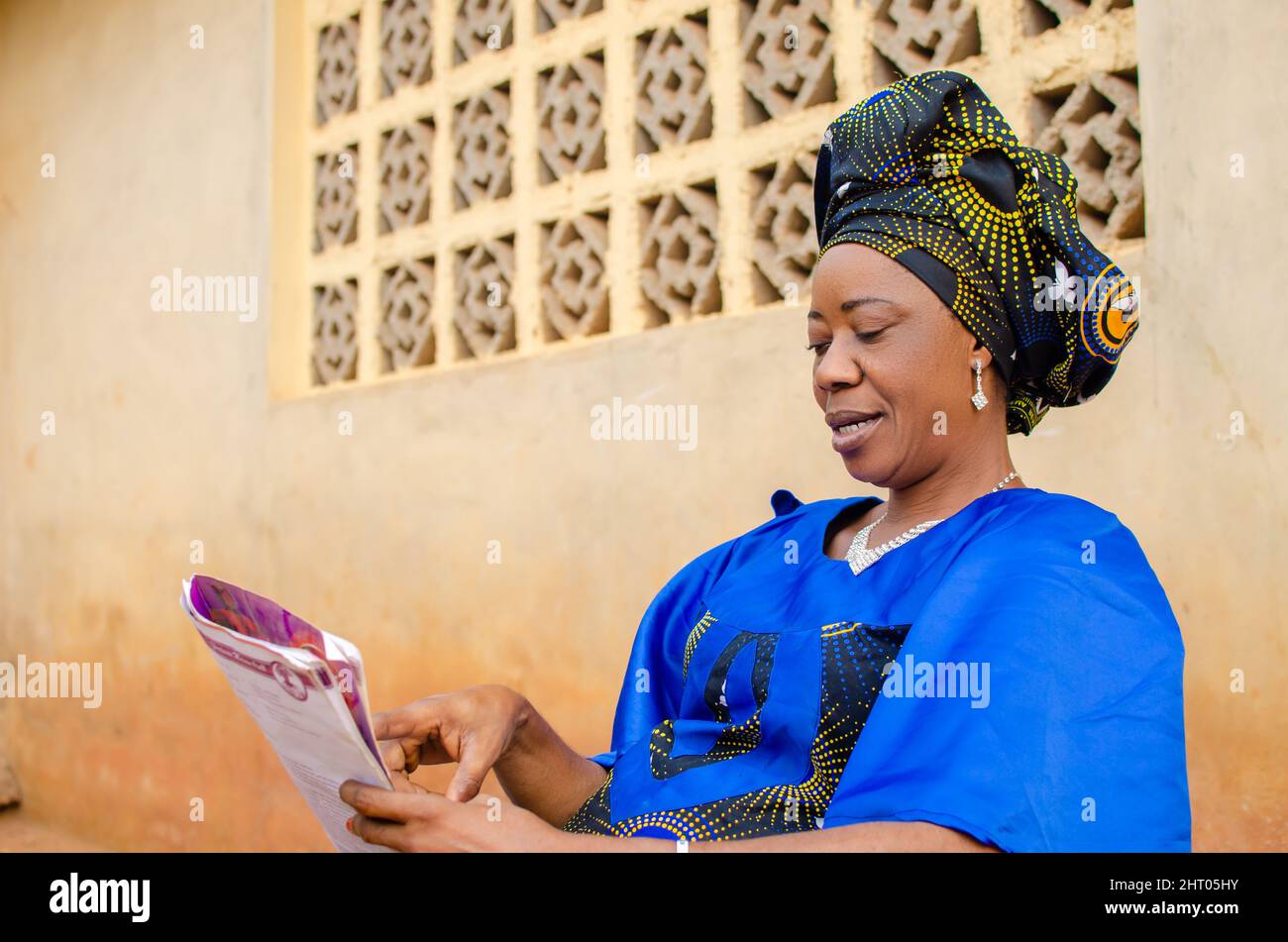Smiling African woman with a bonnet reading a magazine Stock Photo - Alamy