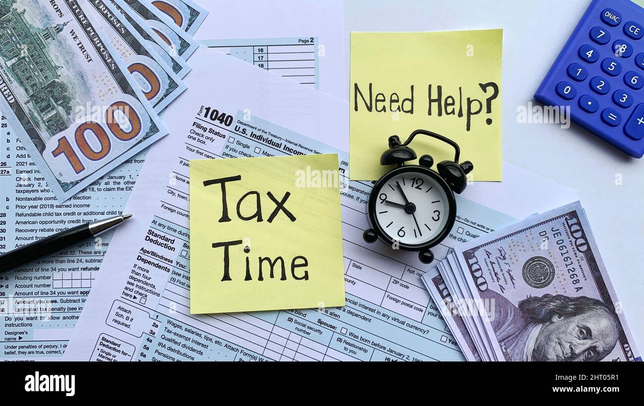 Top view of text on yellow notepad - Tax time, need help. With tax form ...