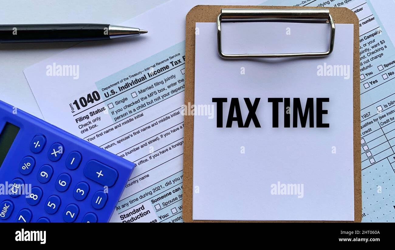 Top view of text on notepad - Tax time. With tax form, calculator and ...