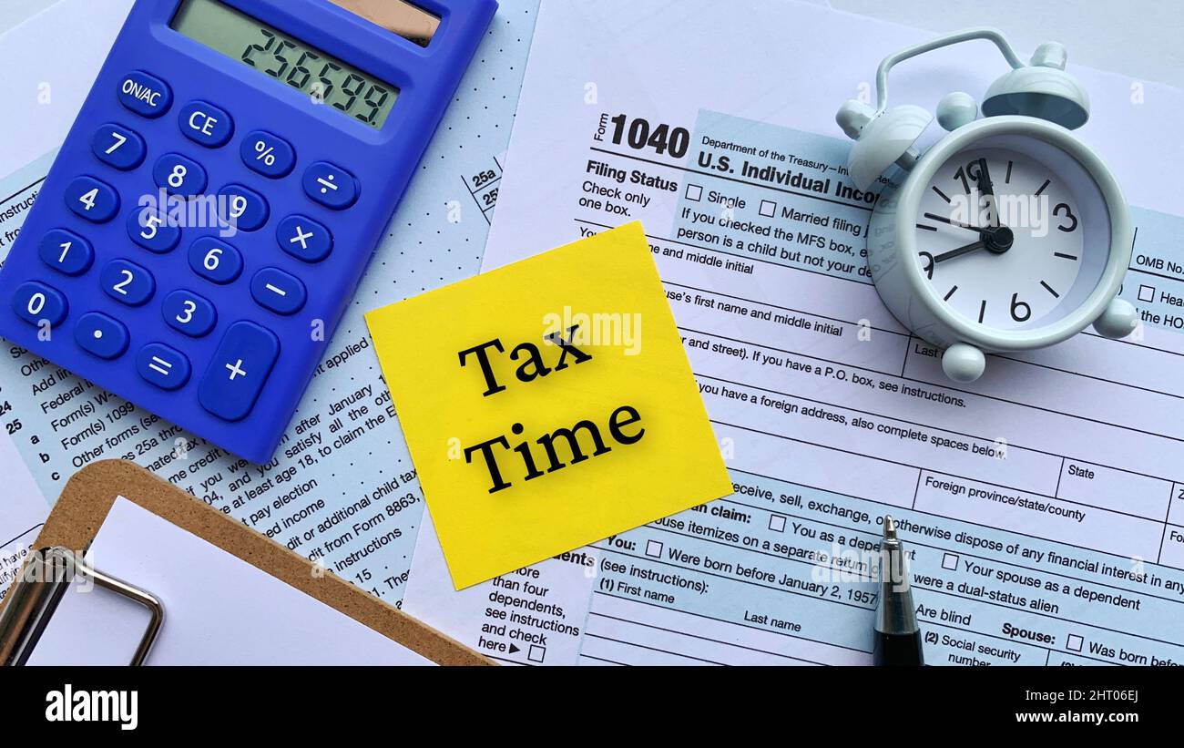 Top view of text on yellow notepad - Tax time. With tax form ...