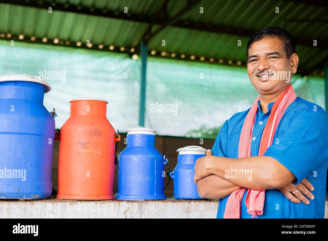 happy smiling diary farmer in front of milk containers at farm house ...