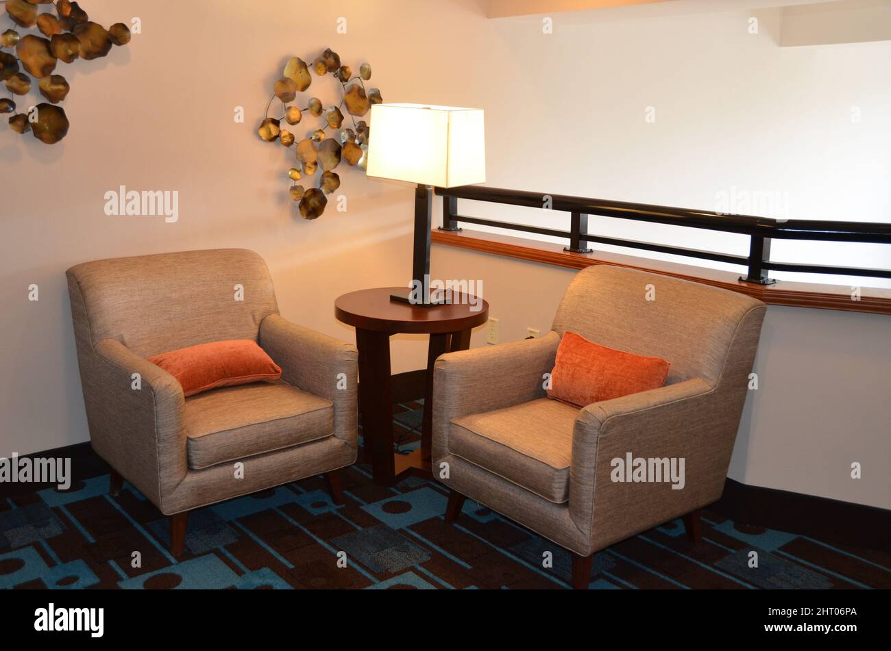 Lobby with two armchairs, a table with a lamp, and wall decors Stock ...