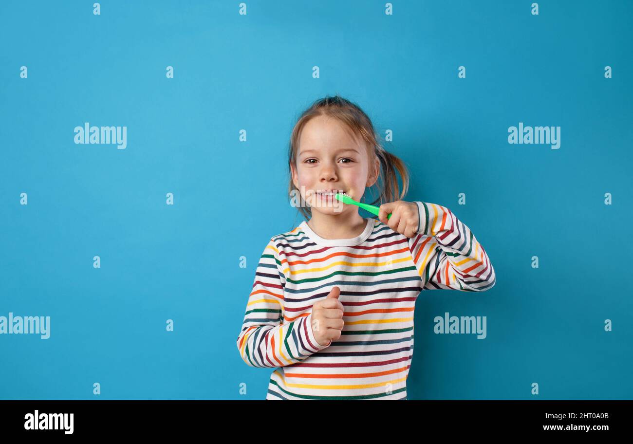 a little girl is brushing her teeth with a toothbrush on a blue ...