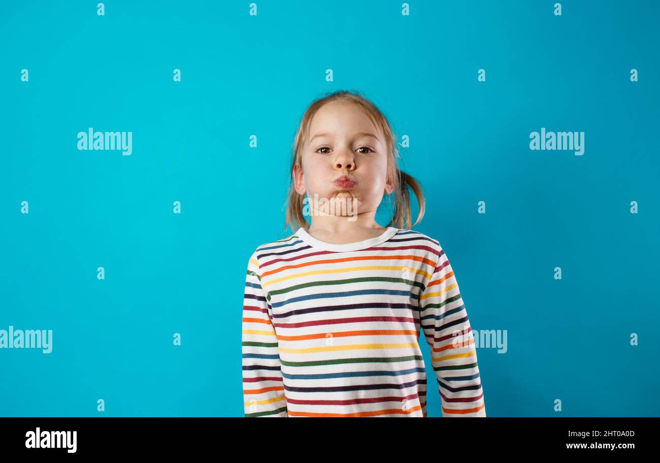 a little girl puffs her cheeks on an isolated blue background Stock ...