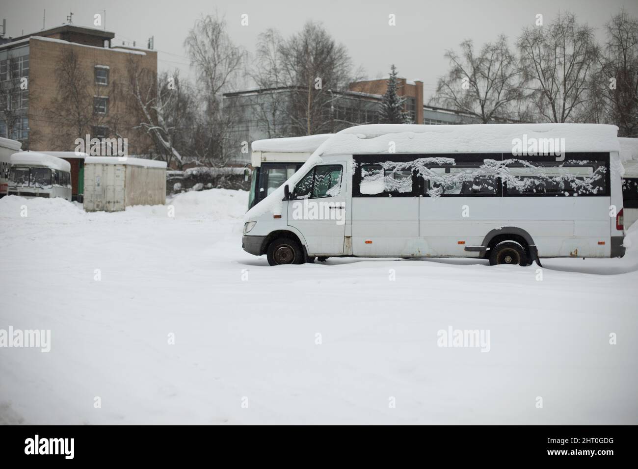 Buses in winter. Bus station in snow. White cars in parking lot. Public ...