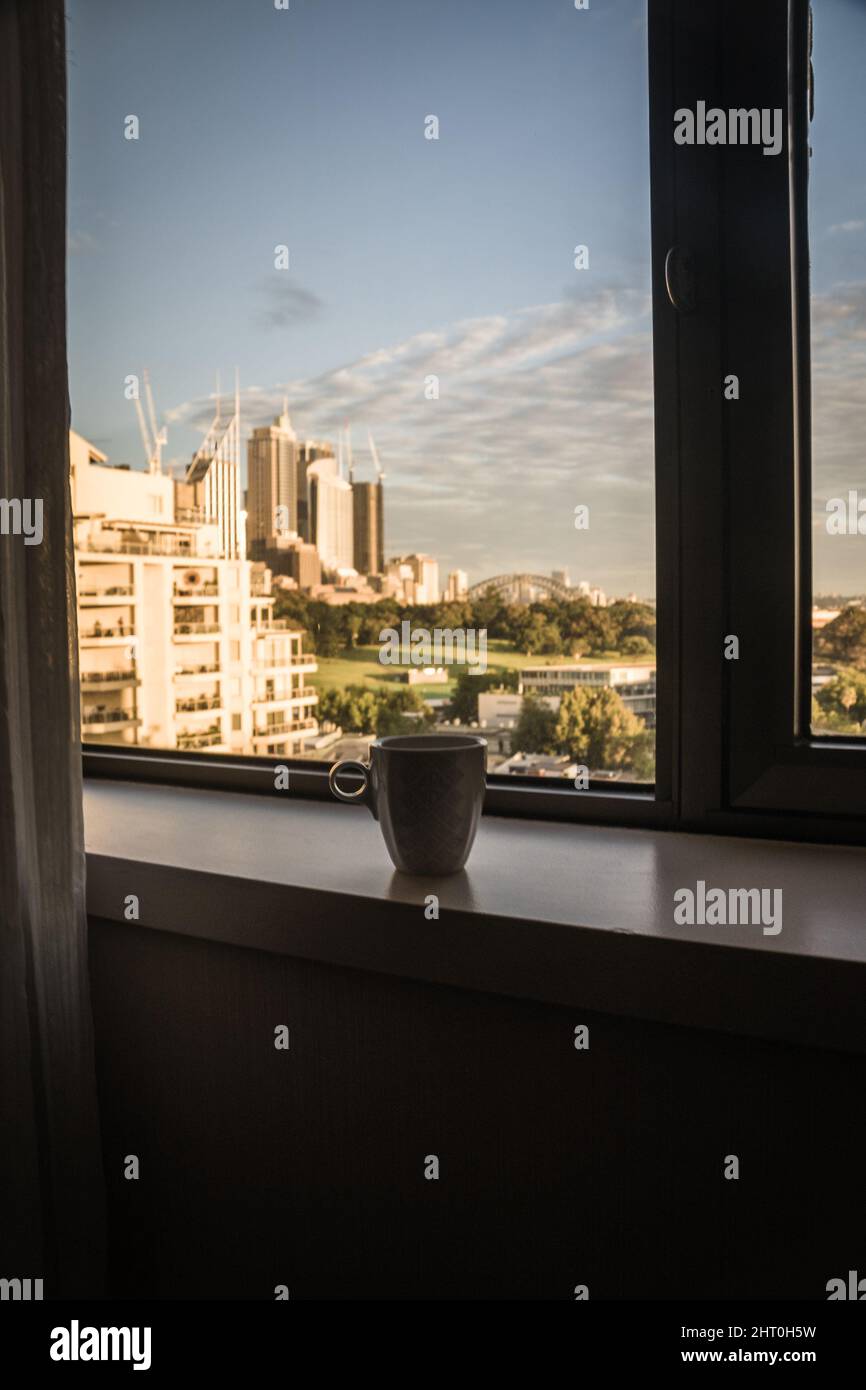 Vertical shot of a white cup on a window on a window sill and a ...
