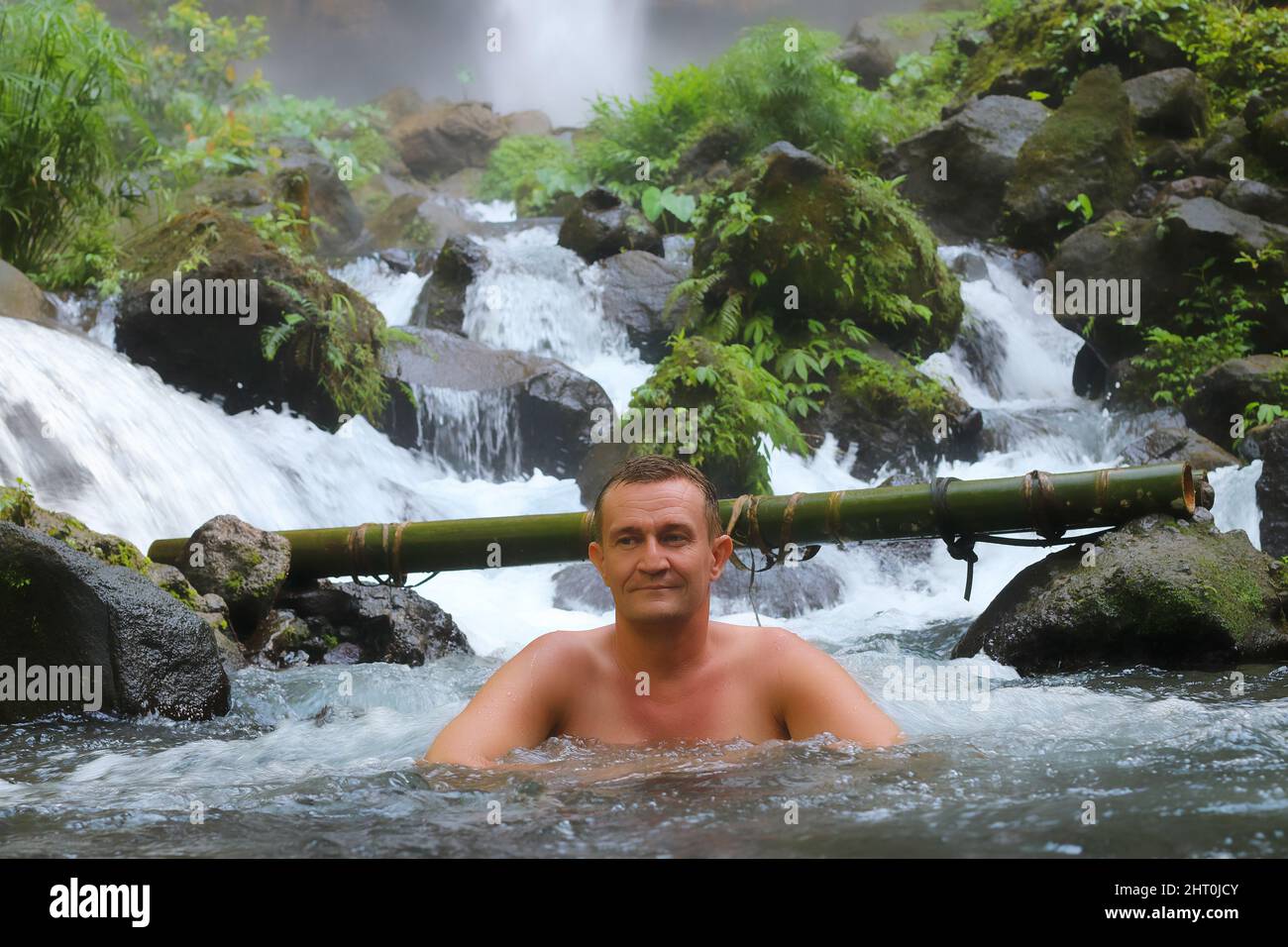 Happy middle aged man resting in stream canyon river in the mountains ...
