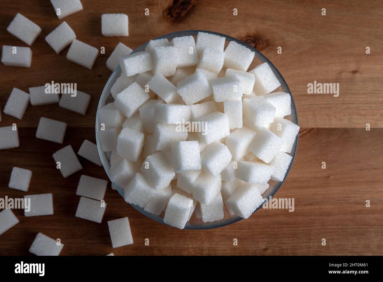 Top view of white sugar cubes in glass bowl full, wooden background ...