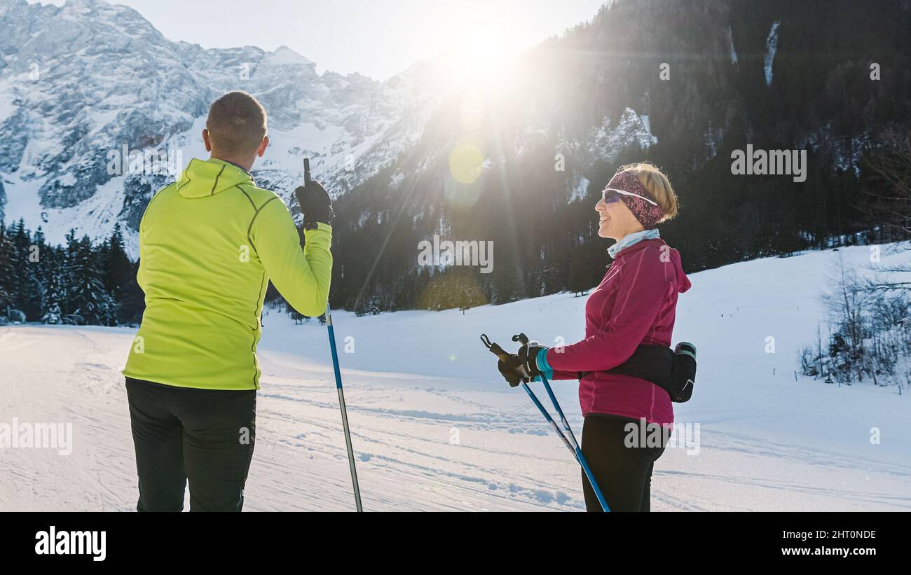 Mature couple, cross country skiers, standing on a ski trail and ...