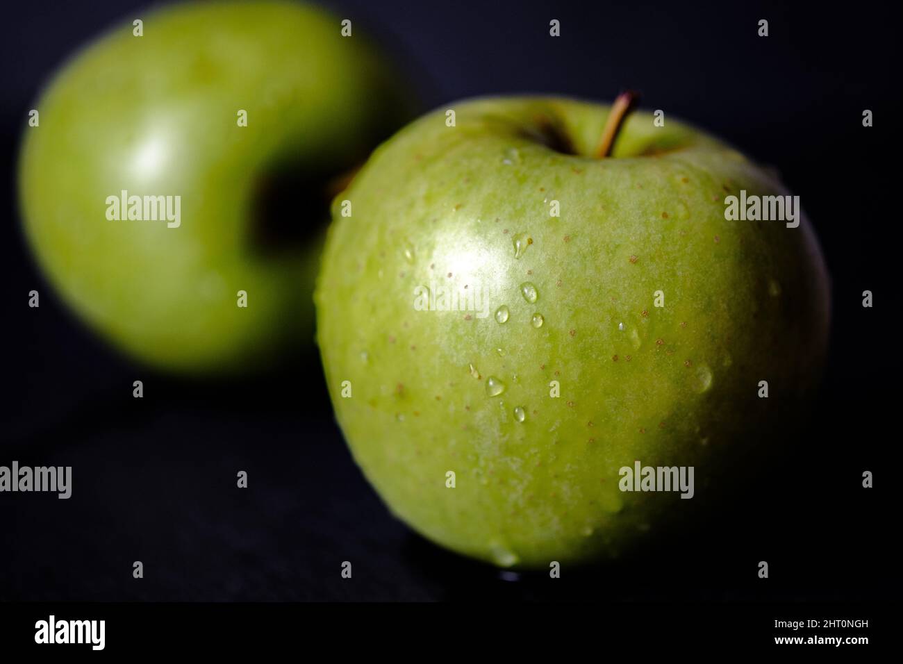 Green apple, fresh and wet fruit isolated on black background gloomy ...
