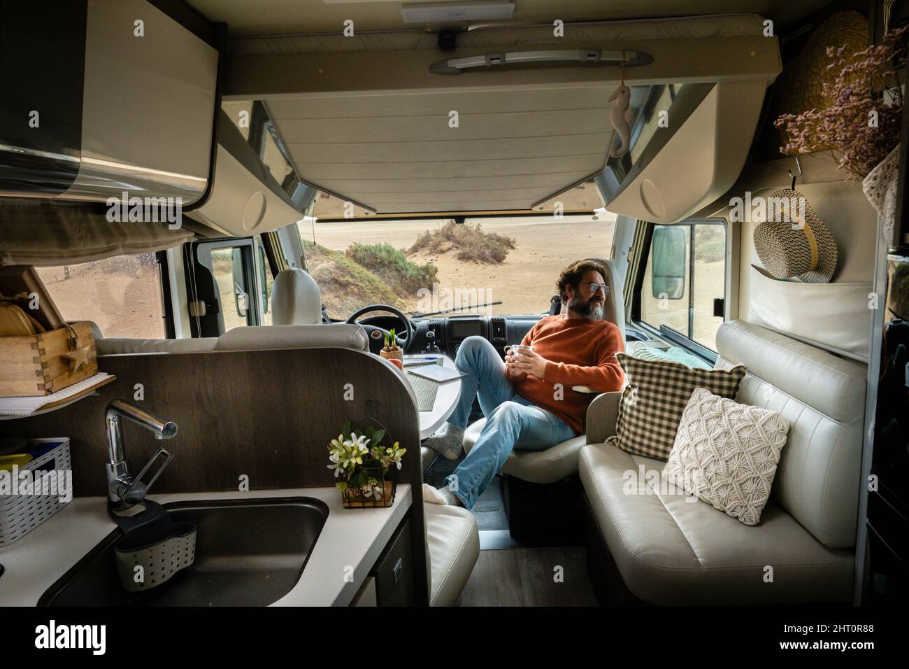 Adult traveler man sit down inside modern cozy mobile home camper van ...
