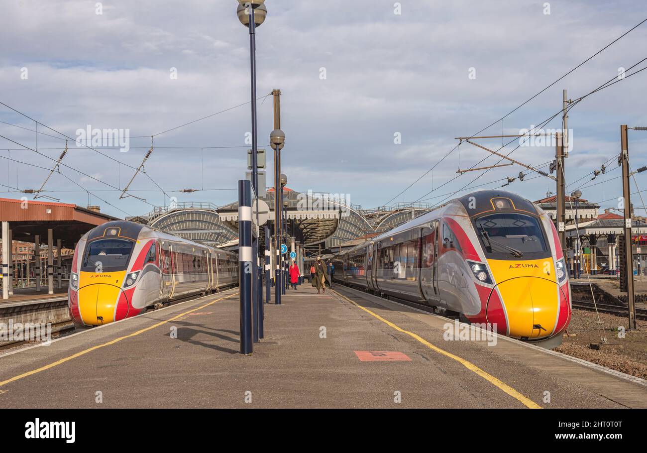 Two trains rest at a railway station platform with historic canopies ...