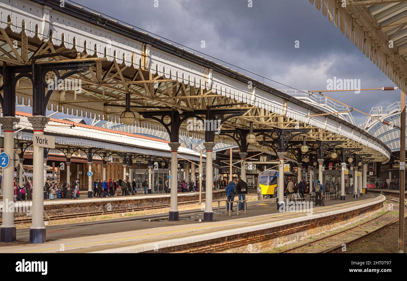 Railway station platform with passengers waiting for a train. Overhead ...