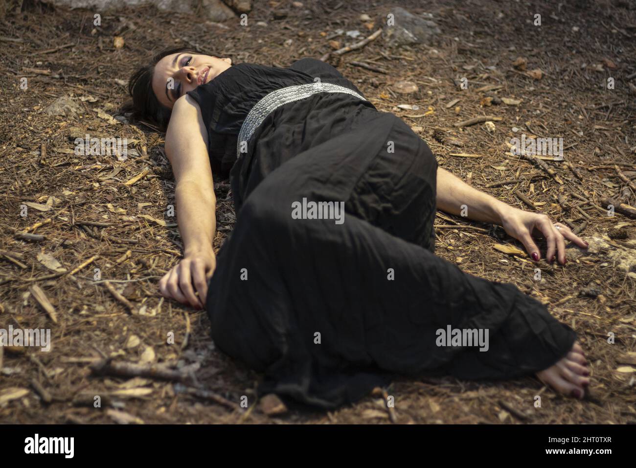 Young female in a black dress lying unconscious in a forest Stock Photo ...