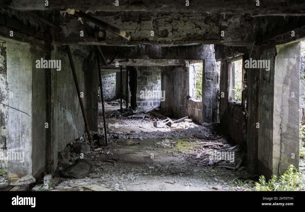 Empty and dark hallway with rubbles and concrete walls in an abandoned ...