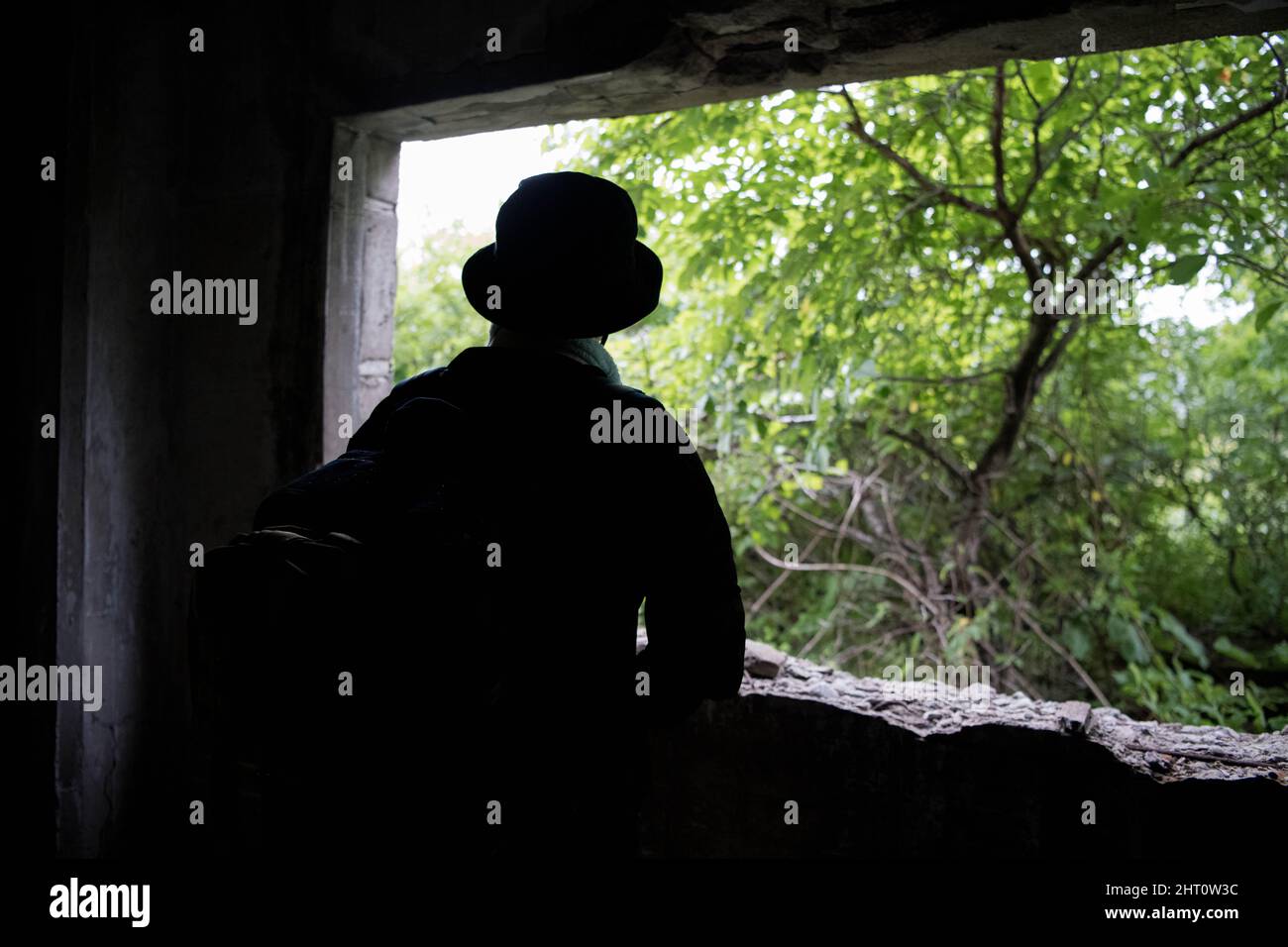 a silhouette of an young male explorer looking out a window without ...