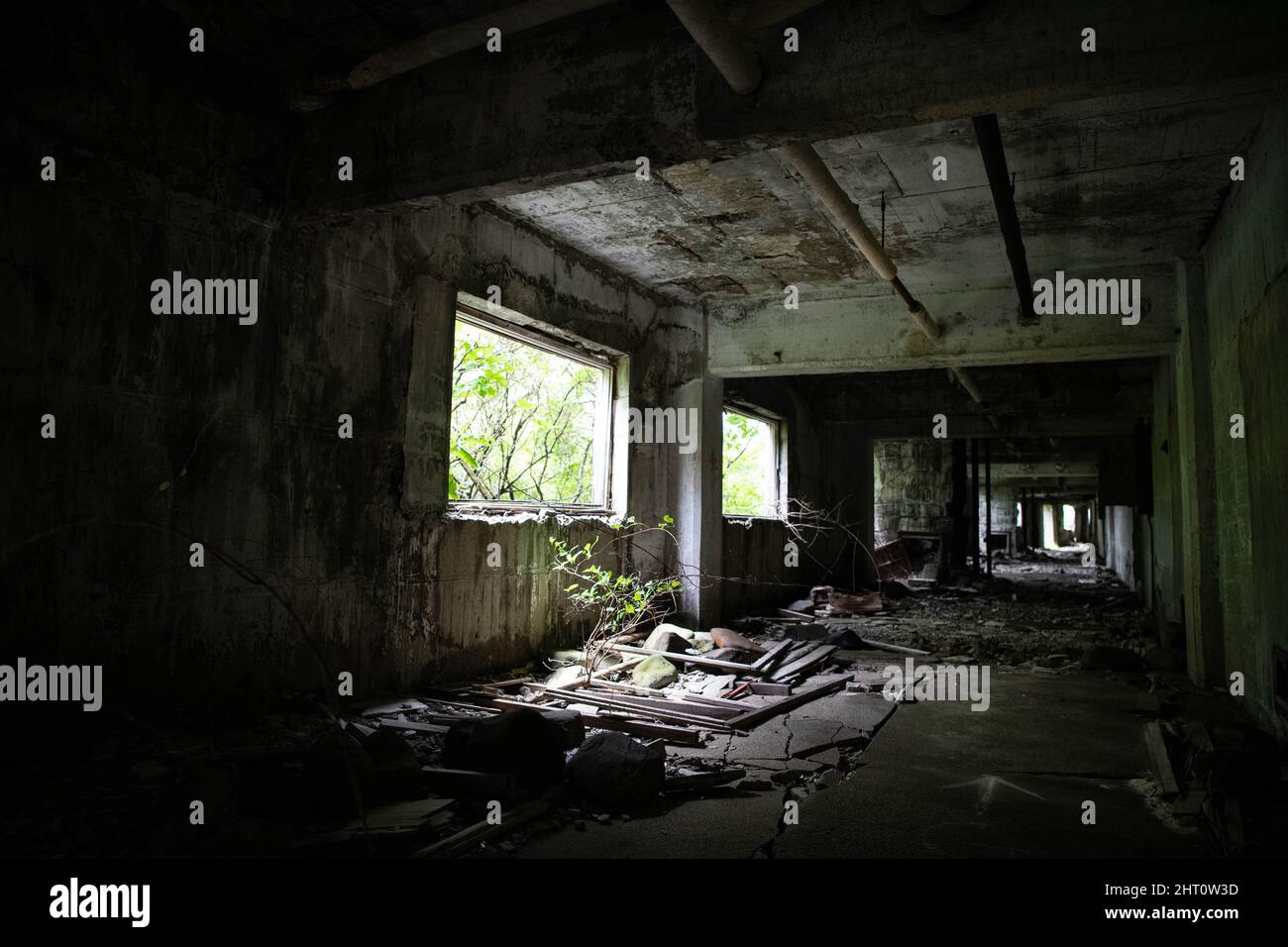 Empty and dark hallway with rubbles and concrete walls in an abandoned ...